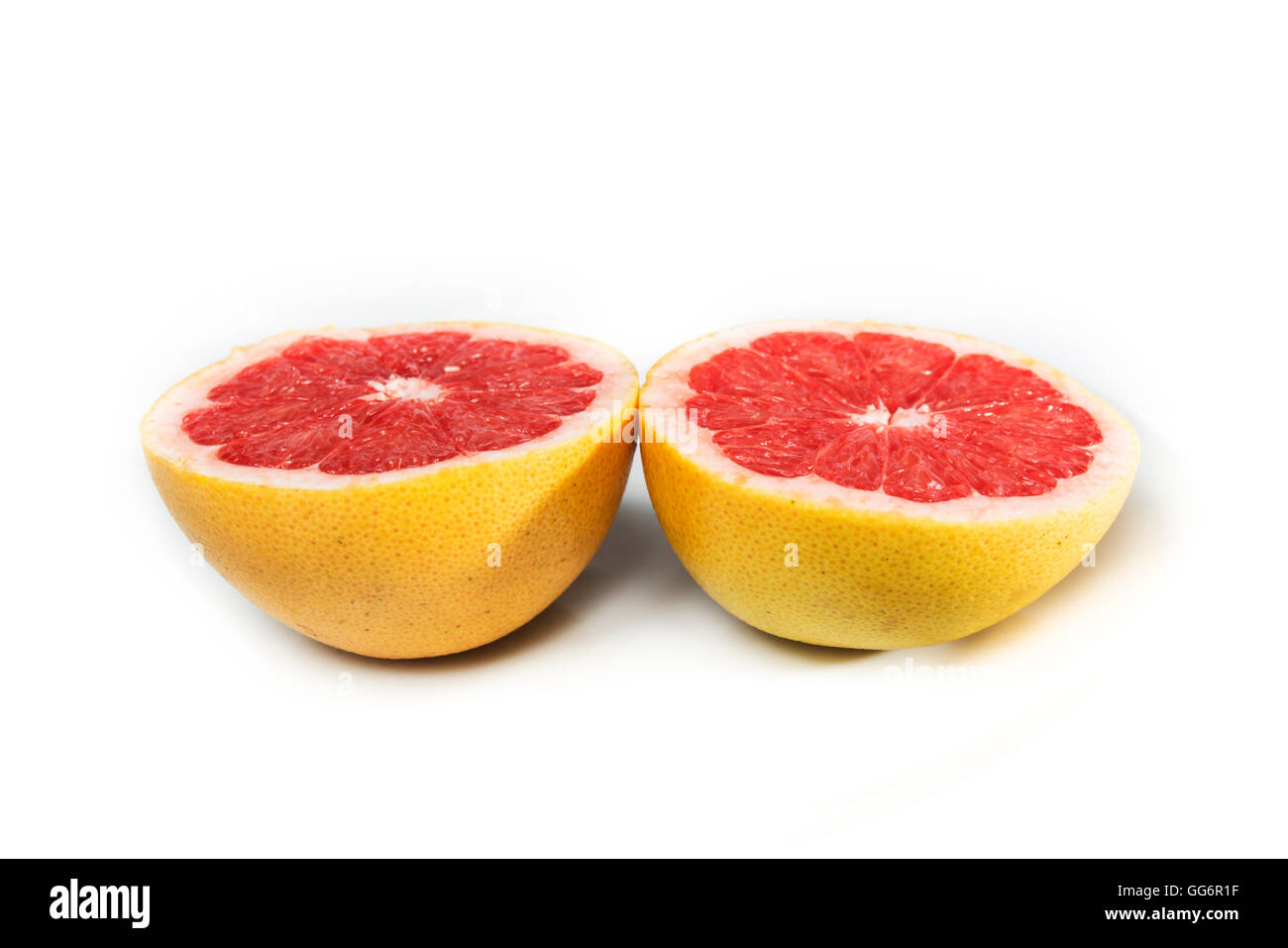 grapefruit split in two halves, outside yellow, red interior, on white ...