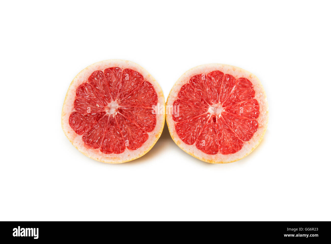 grapefruit split in two halves, outside yellow, red interior, on white ...