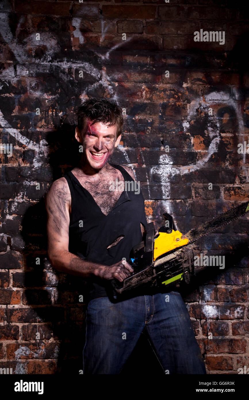 horrific madman on a dark background and gasoline-powered saw Stock ...