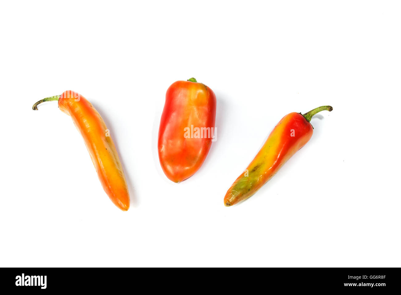 three red peppers of different shapes on white background Stock Photo ...
