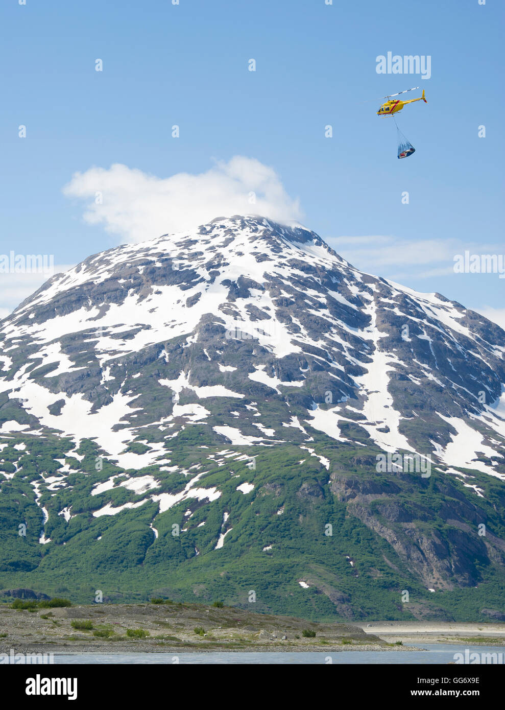 Helicopter flying a load of rafting gear over the Tweedsmuir Glacier ...