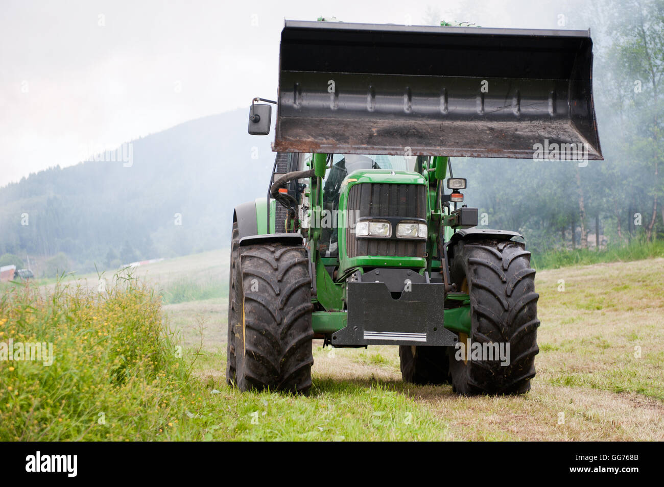 A green huge tractor driving on the field in Norway Stock Photo - Alamy