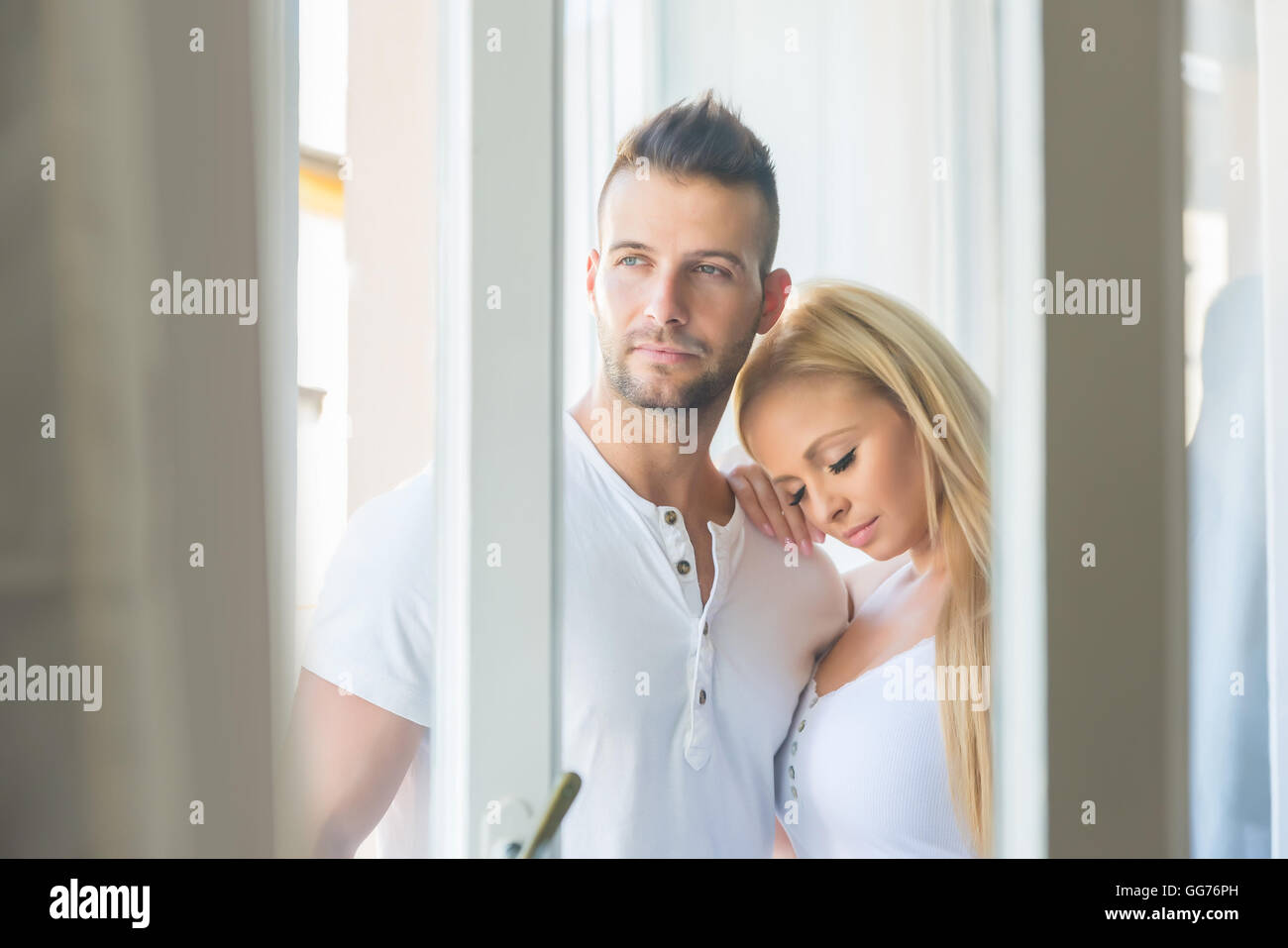 A beautiful young couple standing at the window at home Stock Photo - Alamy