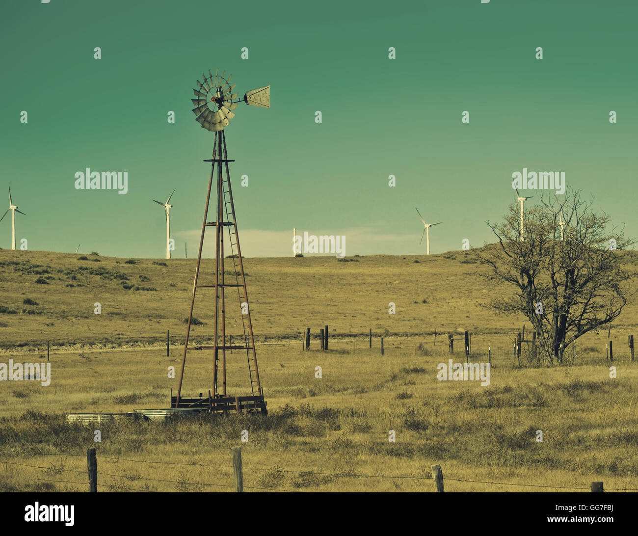 An old wind driven water well is surrounded by new wind generators ...