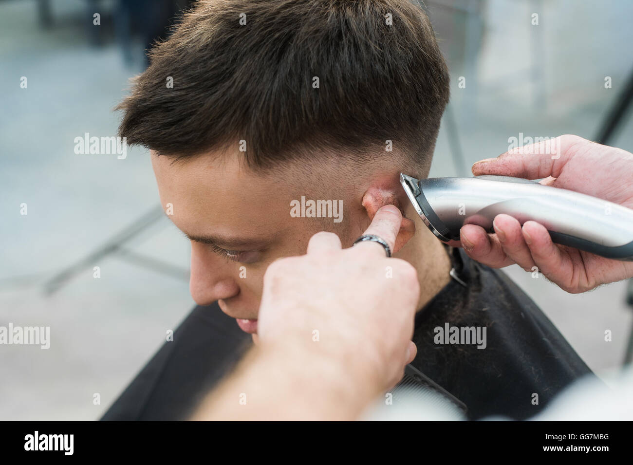 Professional styling. Close up side view of young man getting haircut ...