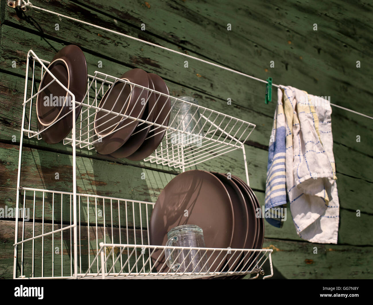 Clean washed dish ware drying on a drainer mounted on the wooden wall ...