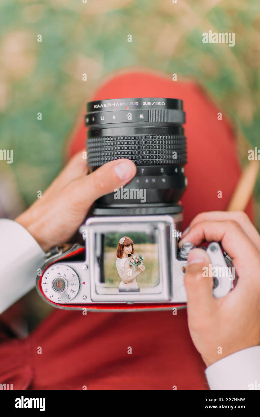 Stylish handsome groom holding medium format film camera, taking photo ...