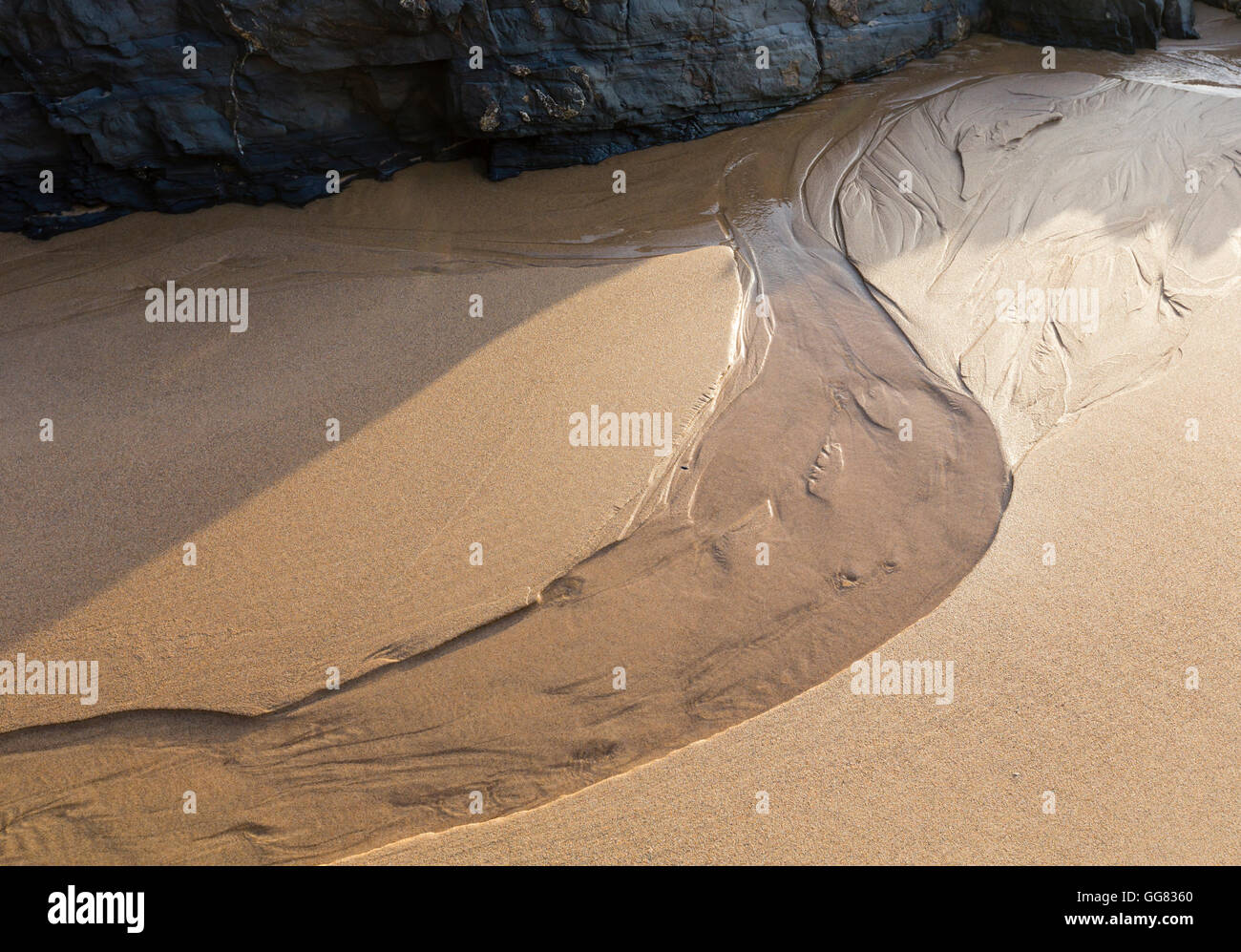 Rock and small steam on sandy beach Stock Photo - Alamy