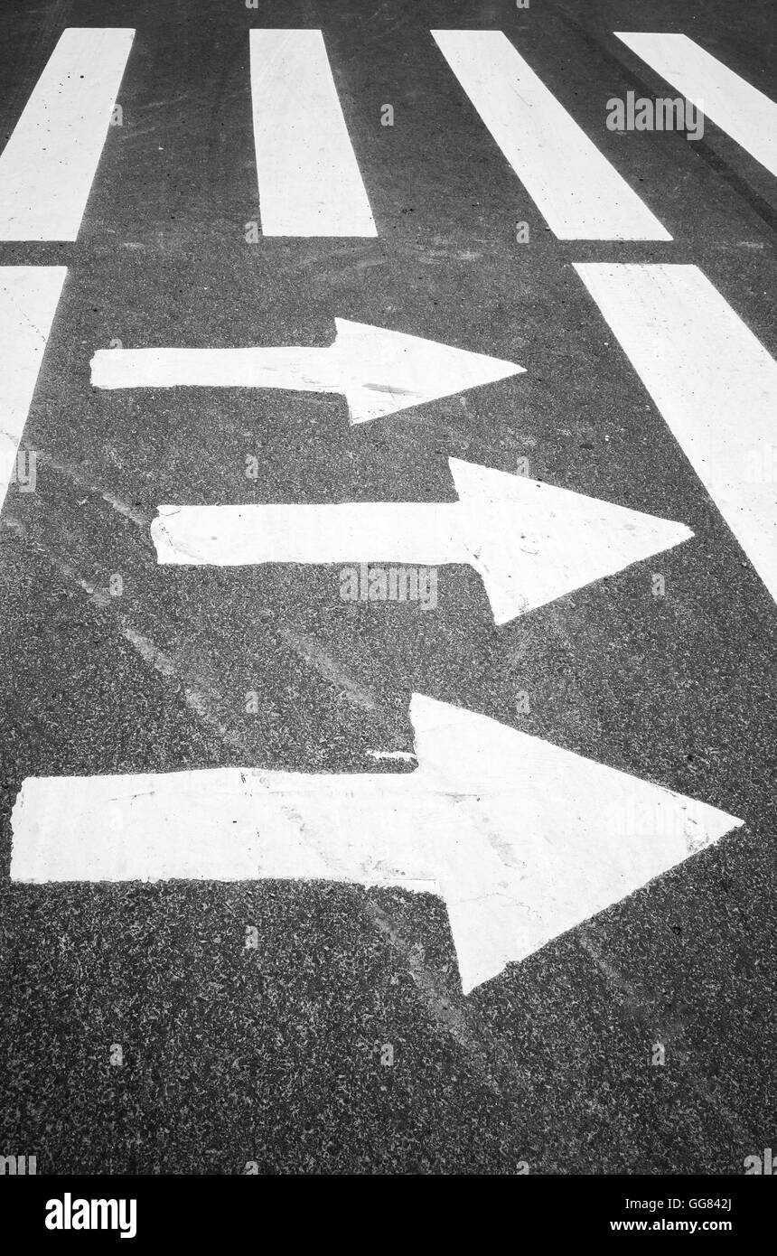 White arrows and stripes over black asphalt road, pedestrian crossing ...