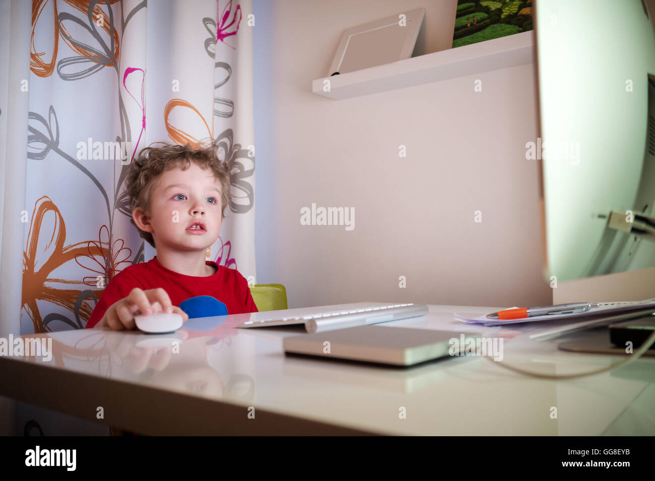 closeup view of young boy playing with computer at night lit by the ...