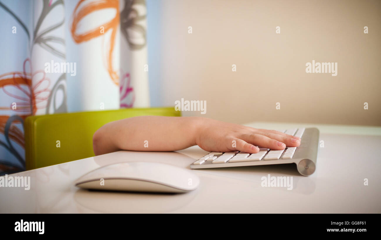 closeup of young boy's hand touching computer keypad while being under ...