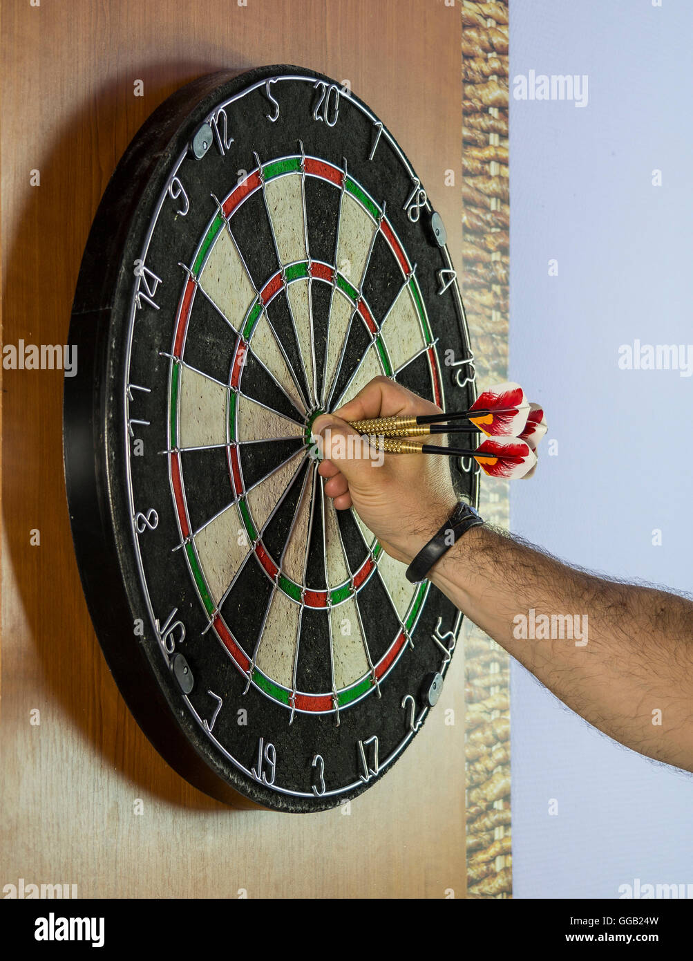 Hand pulling out three darts from a dart board Stock Photo - Alamy