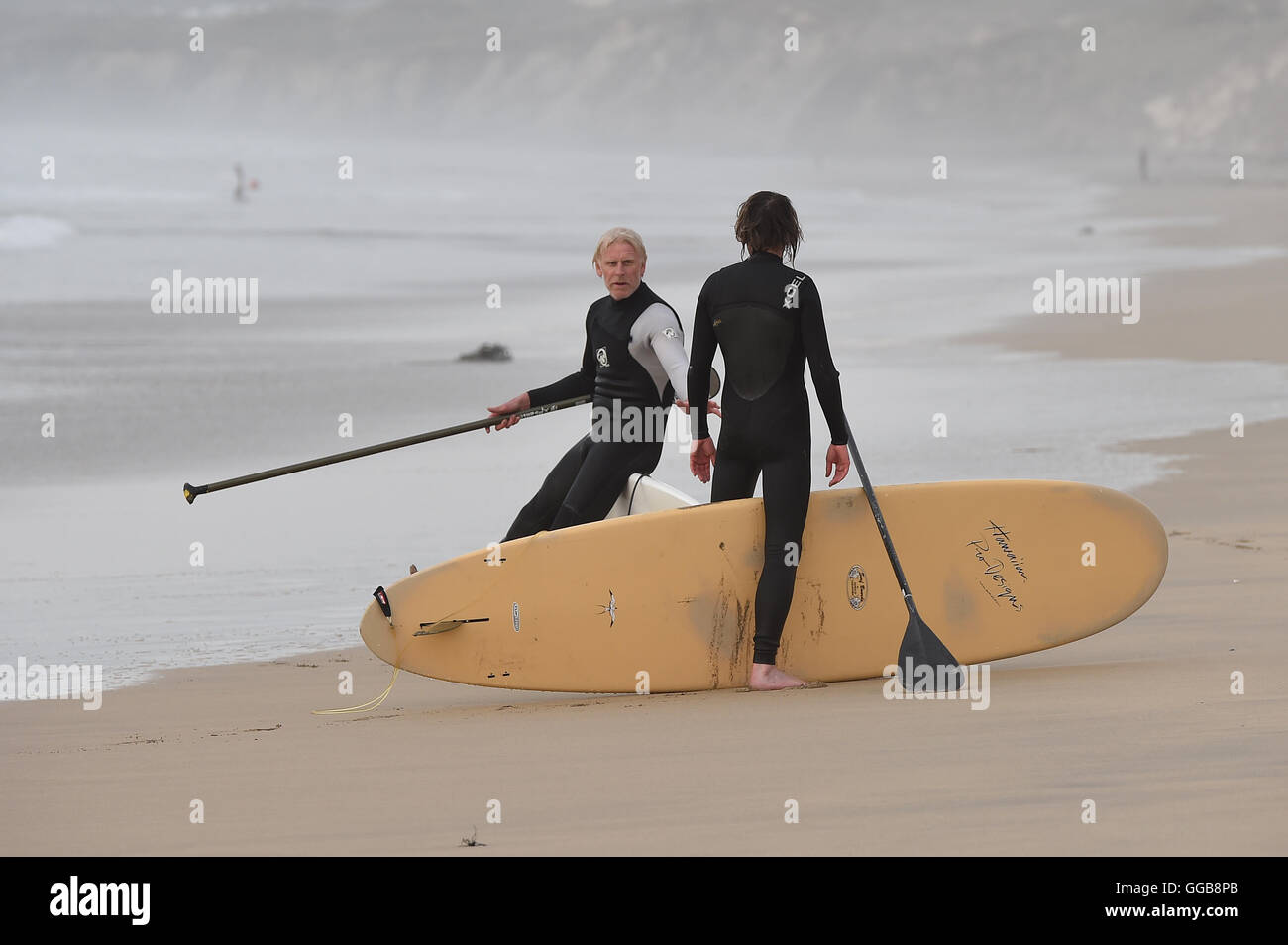 Two surfers relaxing sitting on boards watching the wave sets from the ...