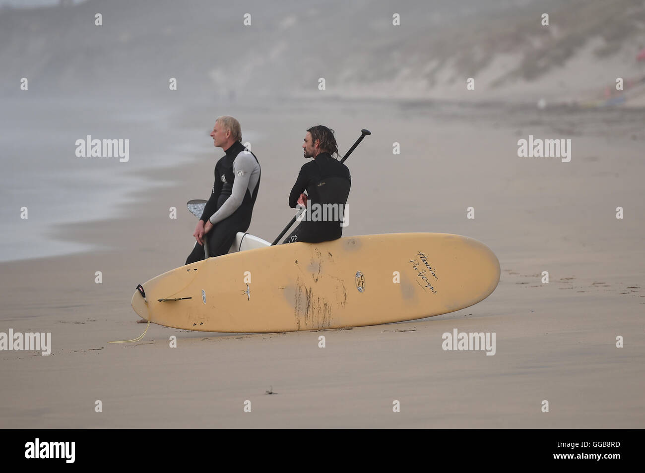 Two surfers relaxing sitting on boards watching the wave sets from the ...