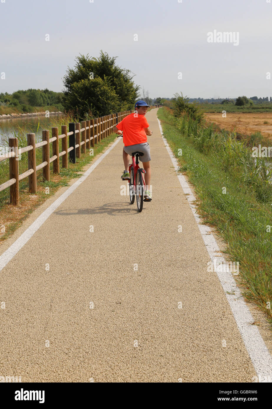 boy riding on the bike path near the lagoon of Venice in summer Stock ...