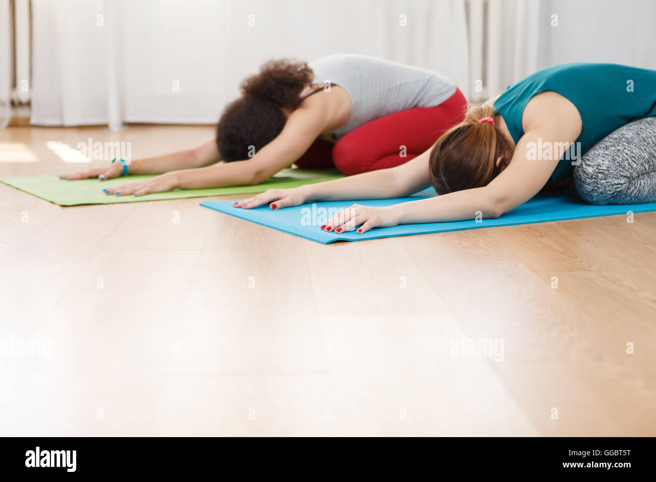 Two women doing yoga asana sitting in forward bend posture Stock Photo ...