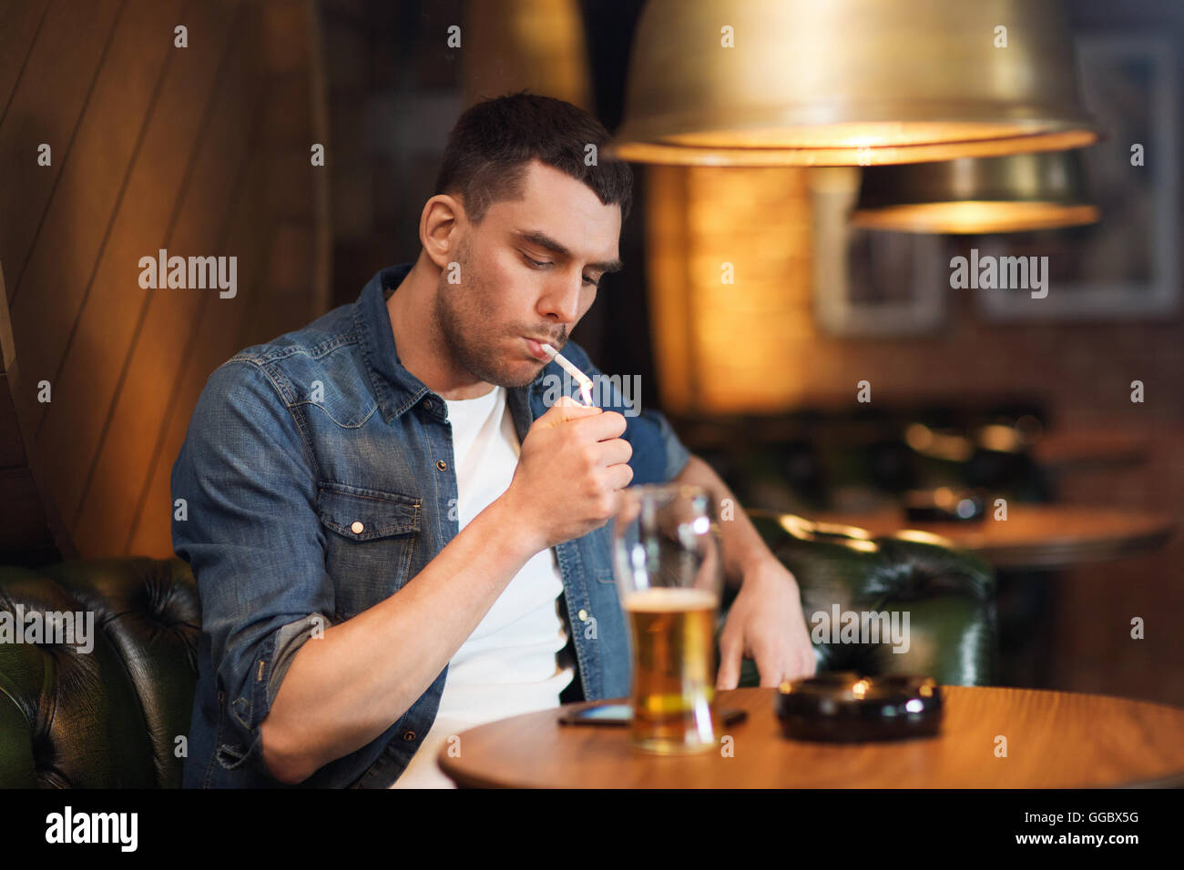 man drinking beer and smoking cigarette at bar Stock Photo - Alamy
