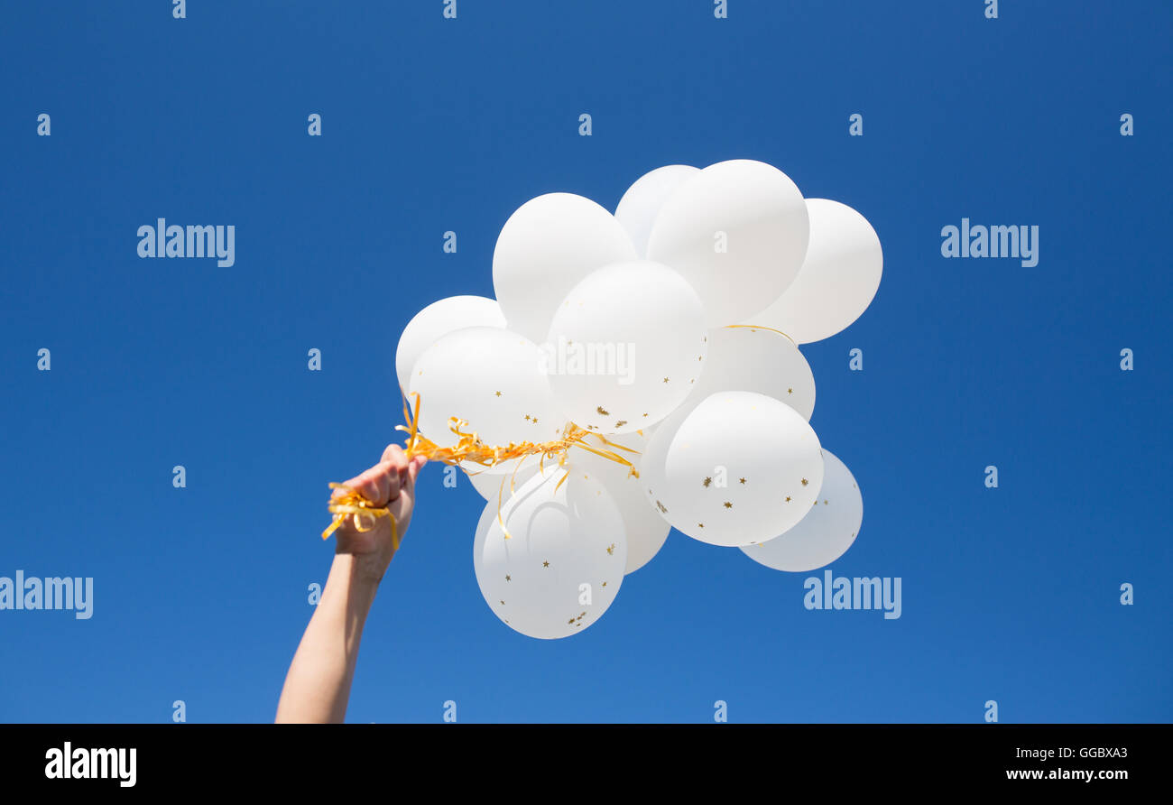 close up of hand with white balloons in blue sky Stock Photo - Alamy