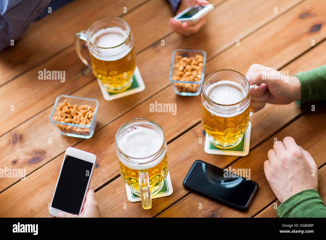 close up of hands with smartphones and beer at bar Stock Photo - Alamy
