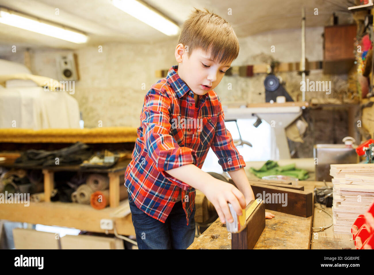 happy little boy with plank and ruler at workshop Stock Photo - Alamy