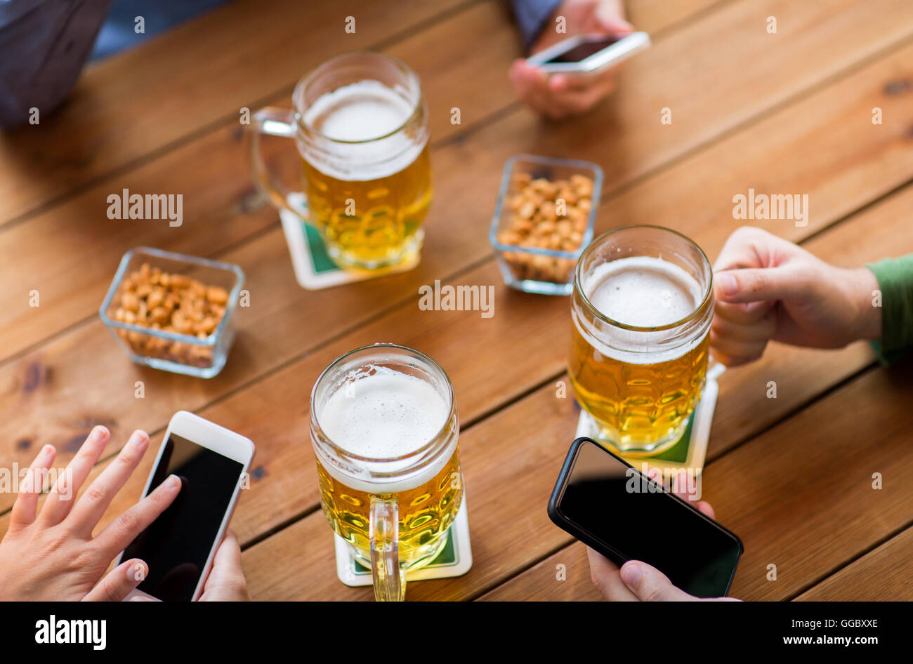 close up of hands with smartphones and beer at bar Stock Photo - Alamy