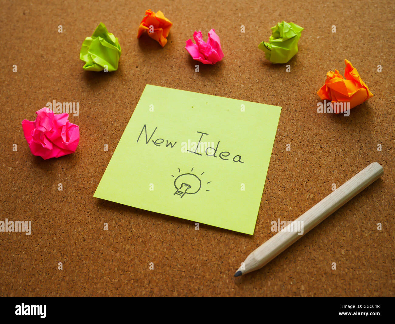 Text new idea in green post note and used post note and pencil on wood ...