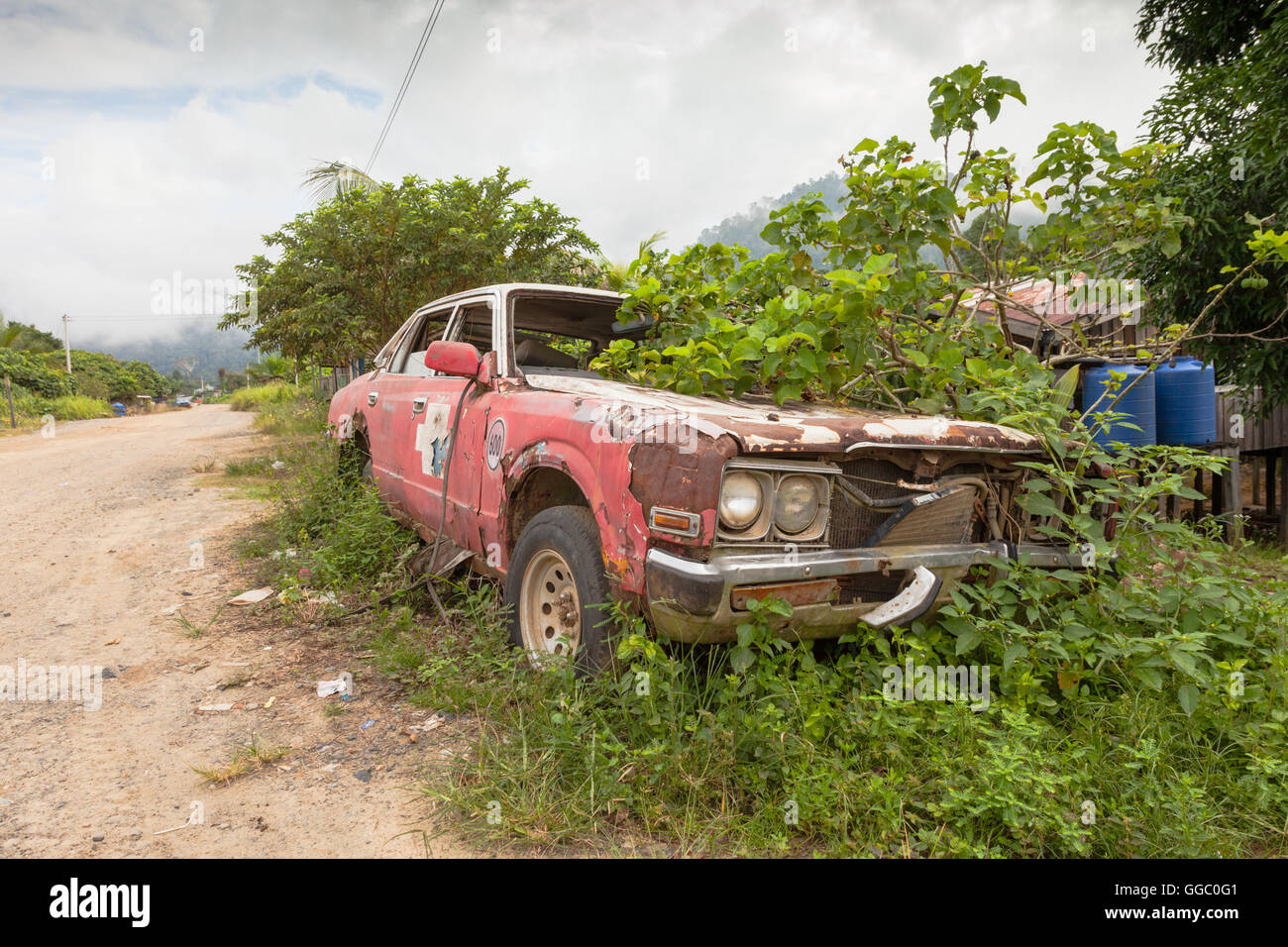 Abandoned car on the side of the road in a remote village in Sabah ...