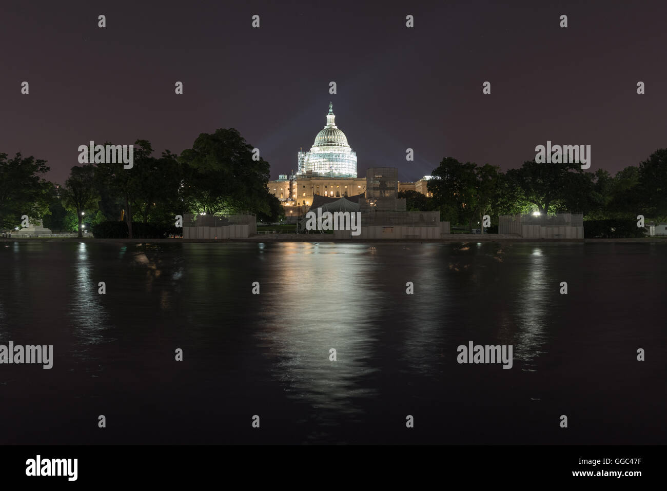 The US Capitol Building under scaffolding as seen across the reflecting ...