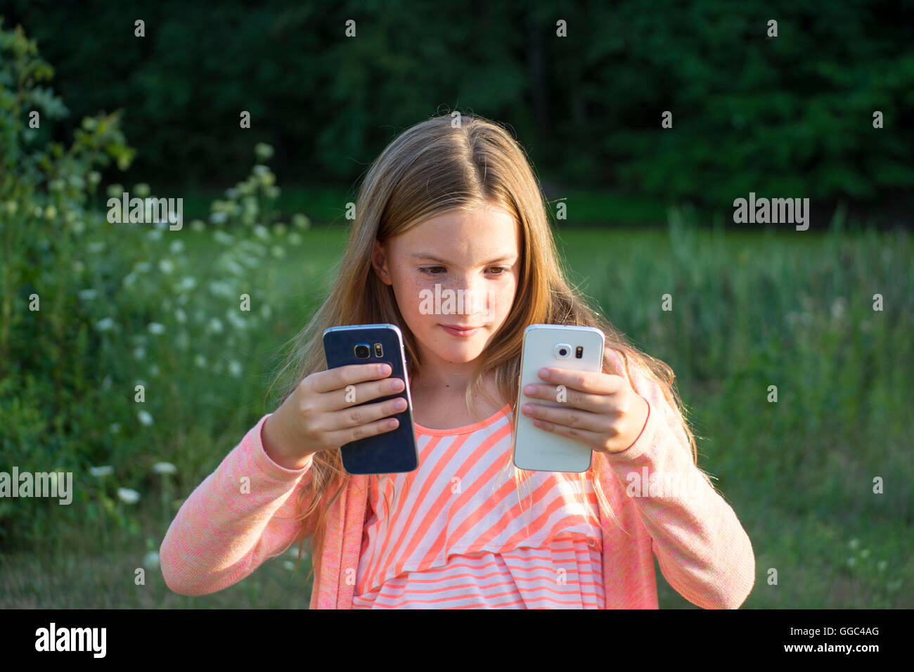 Girl with two cell phones texting Stock Photo - Alamy