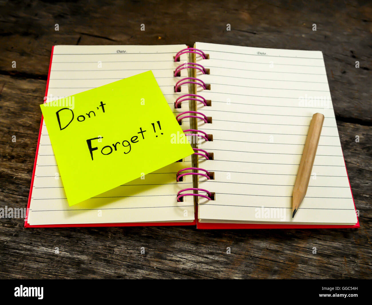 Reminder paper note in note book on wooden table Stock Photo - Alamy