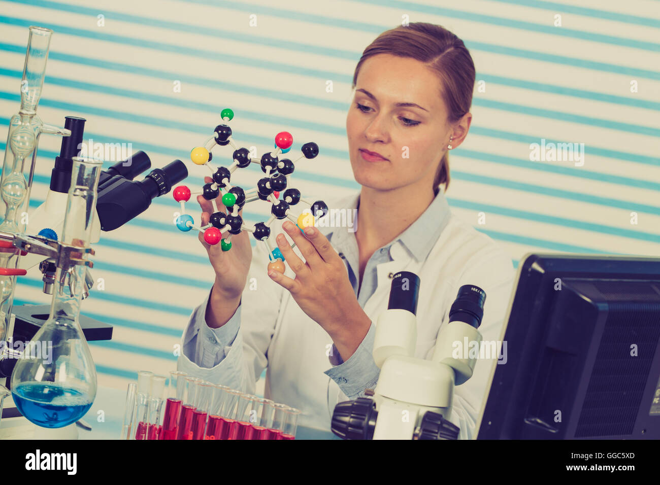 young woman scientist working at the laboratory. Model of molecule on a ...