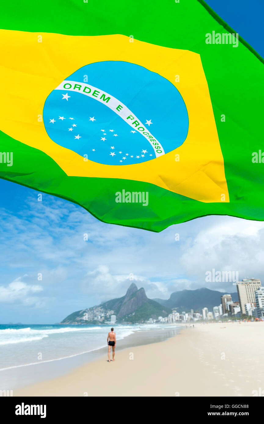 Brazilian flag flying in bright sun above the city skyline at Ipanema ...