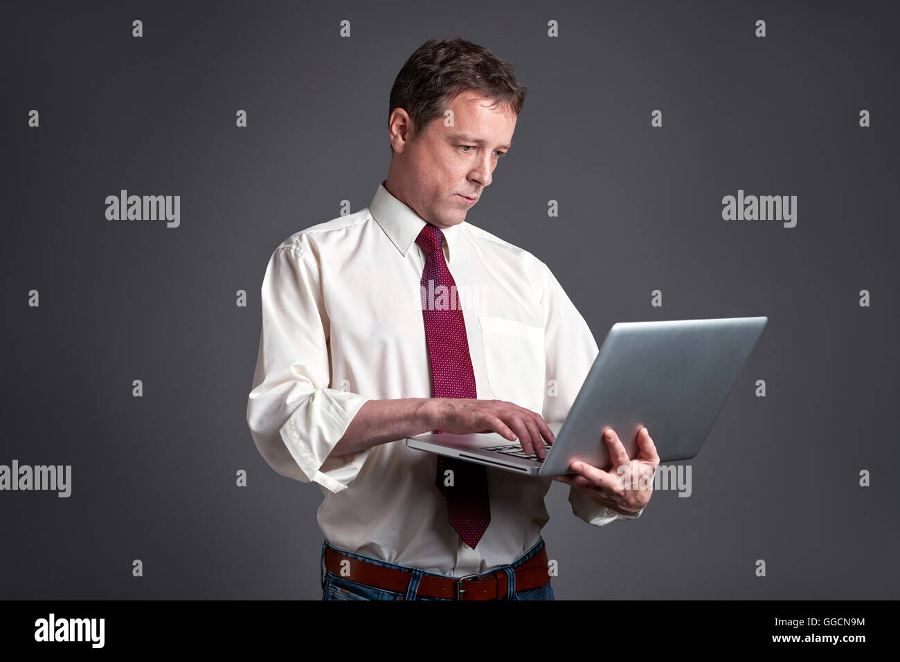 A middle age man standing and using a laptop Stock Photo - Alamy