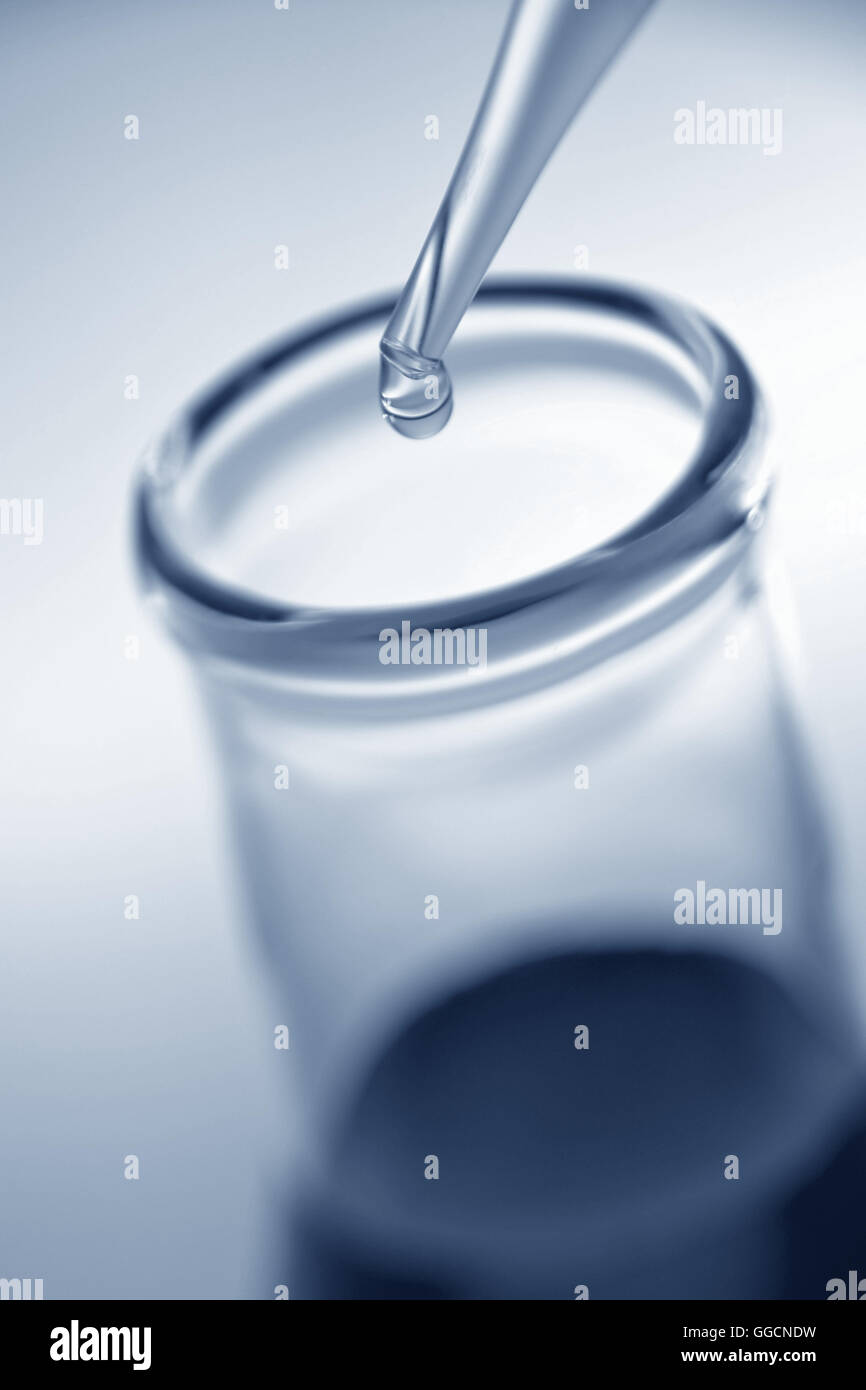 Pipette with drop of liquid over Erlenmeyer flask for an experiment in ...