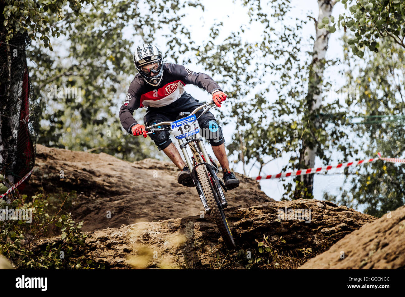 male athlete competitor downhill rides in forest during National ...