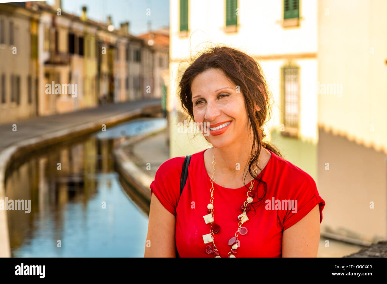 environmental portrait of Mediterranean woman in red dress sitting on ...