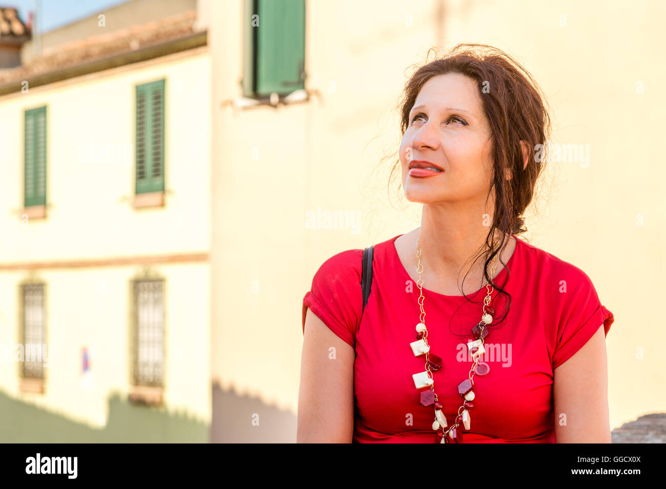 environmental portrait of Mediterranean woman in red dress looking ...