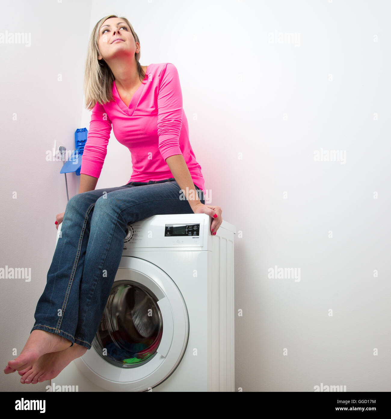 Housework: young woman doing laundry - waiting for the washing program ...