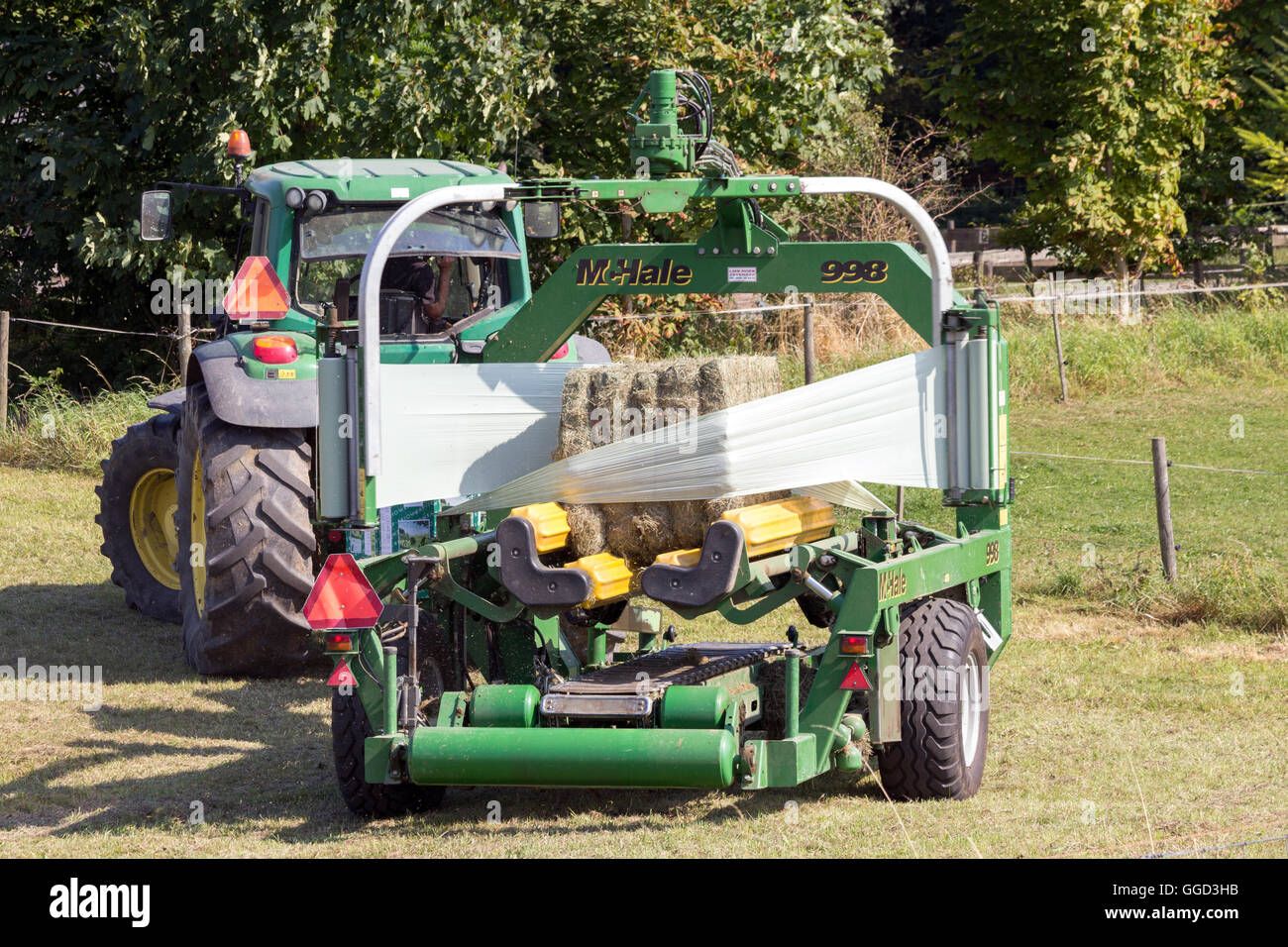 Tractor wrapping a bale of hay in plastic protection Stock Photo - Alamy