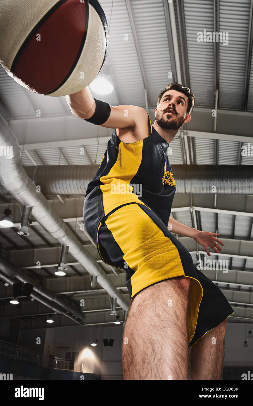 The portrait of a basketball player with ball against gray gym ...