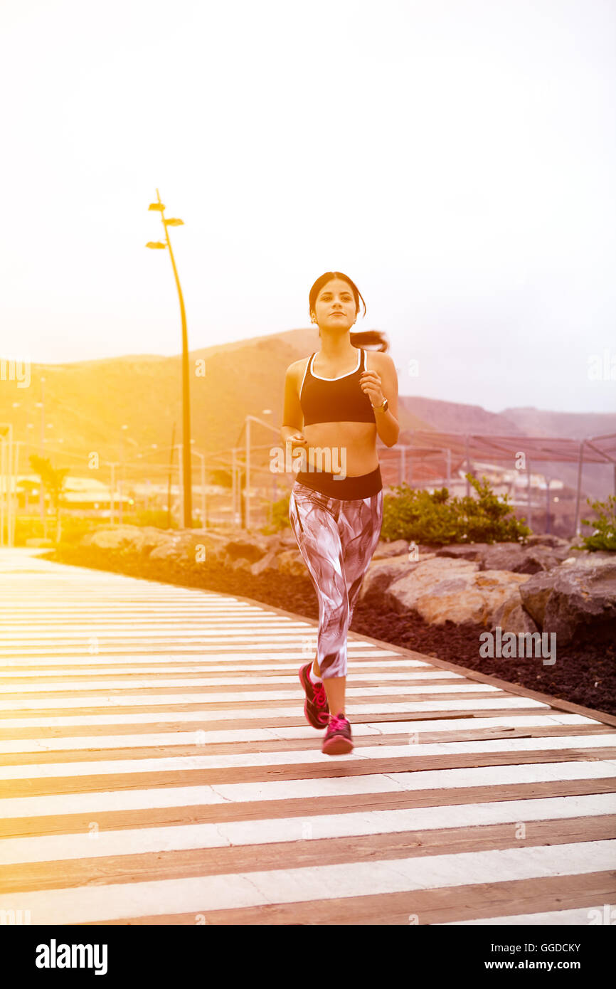 Young girl out for a run on a paved path a coastline behind her ...