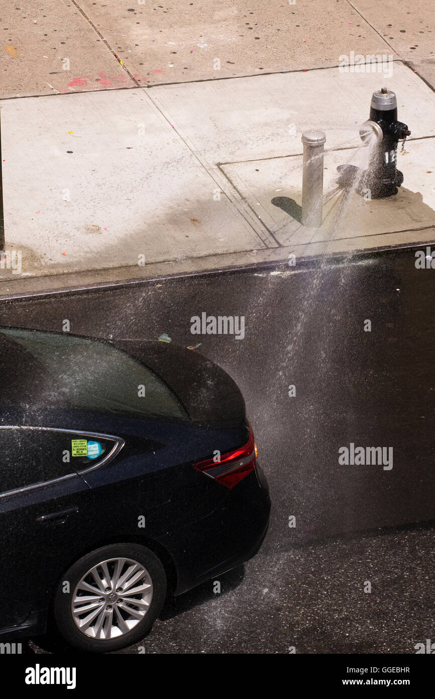 Dark colored Toyota automobile driving through streams of water from an ...