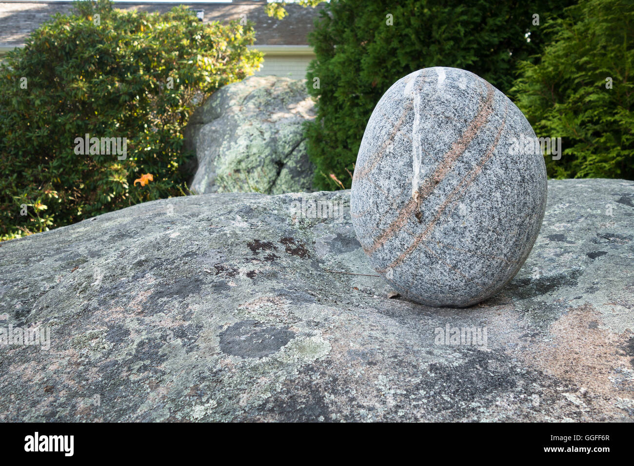 A smooth, oval-shaped stone balances perfectly atop another large ...