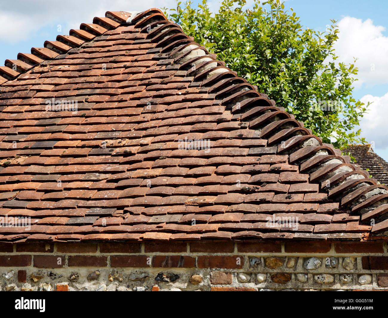 Hipped roof with traditional hand-made flat tiles on a small brick and ...