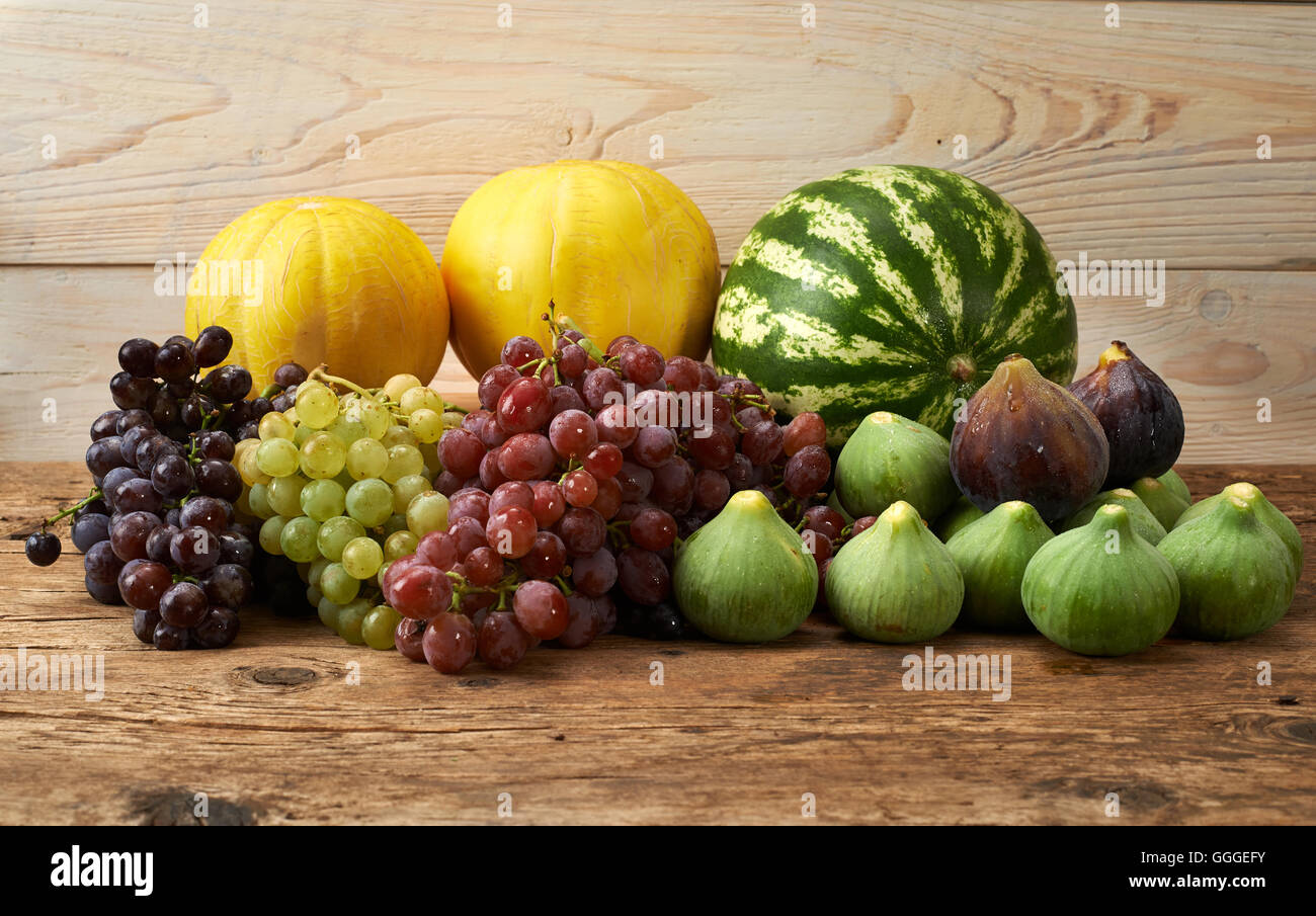 many fresh autumn fruits grape melon watermelon figs on a wooden ...
