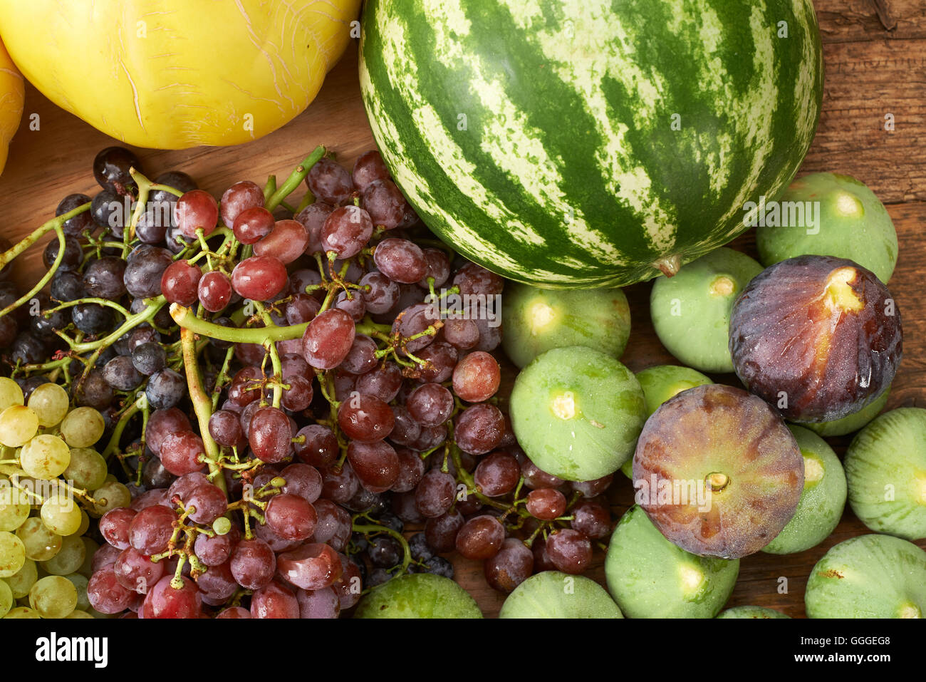 many fresh autumn fruits grape melon watermelon figs on a wooden ...