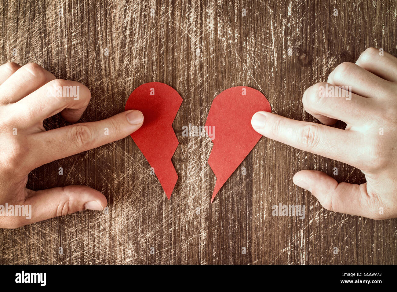 Hands holding two halves of broken heart going to be joined in one ...