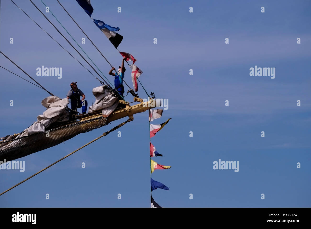 Men hanging different national flags in forestay over a bowsprit of a ...