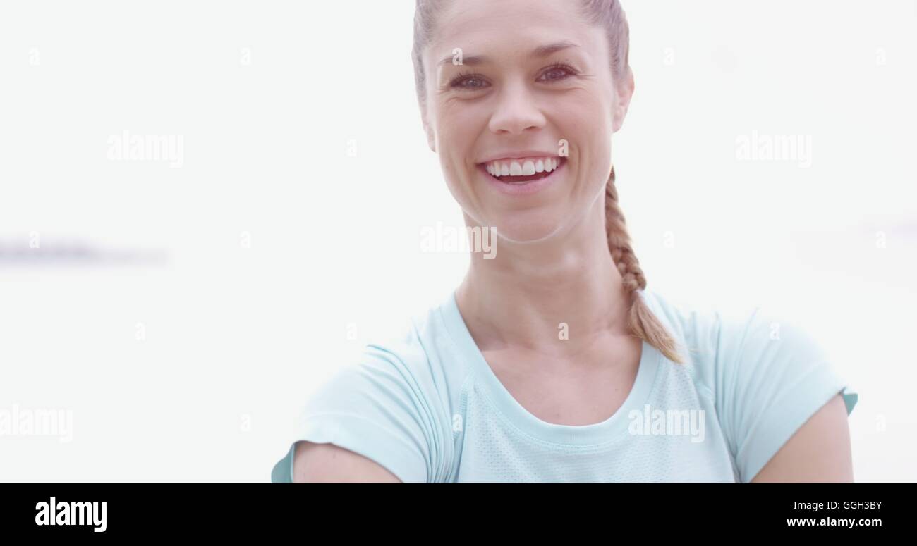 Happy blond woman with her hair in a plait smiling at the camera ...