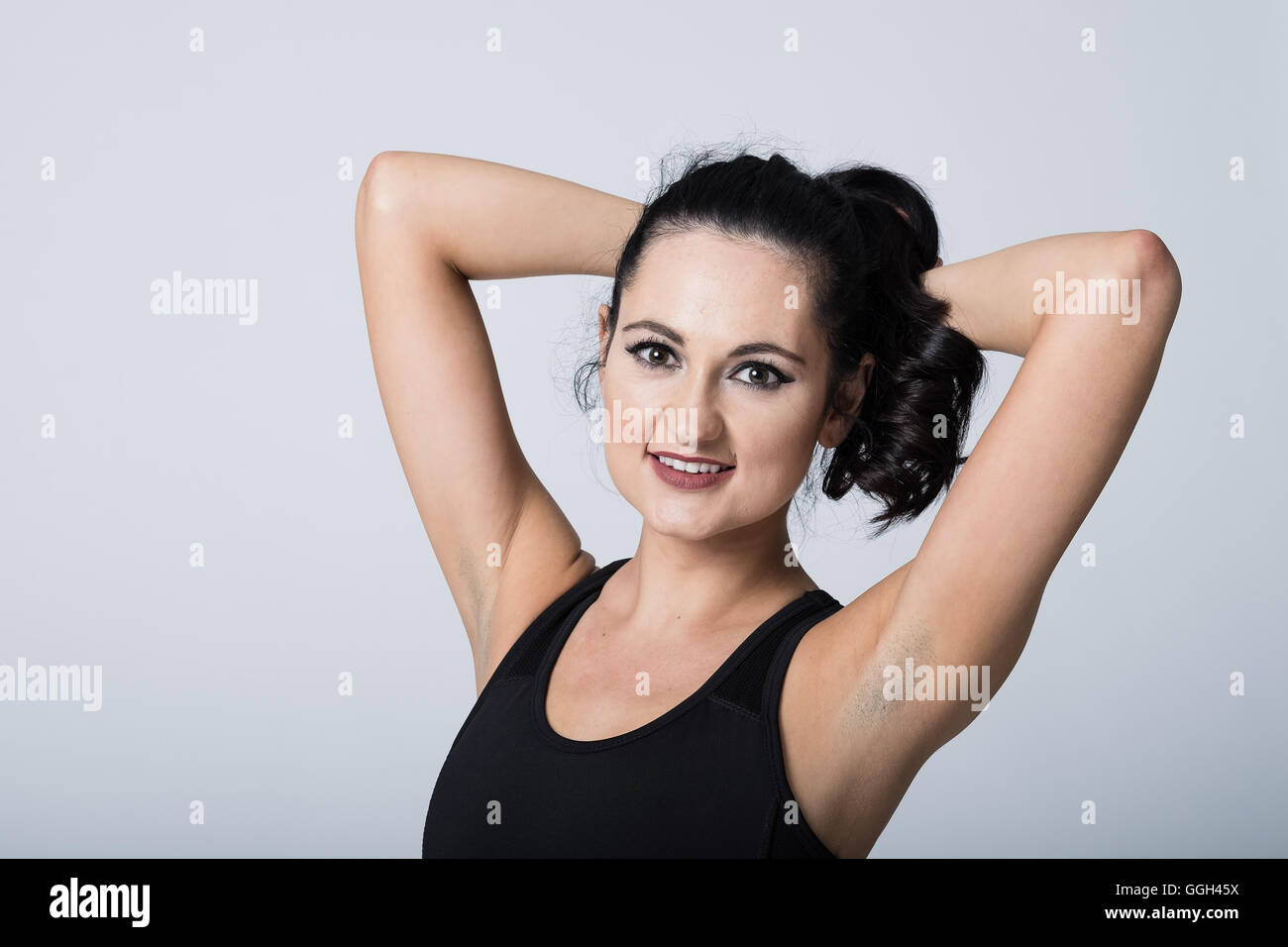 Striking woman in her 20s in smiles and looks at camera in training ...
